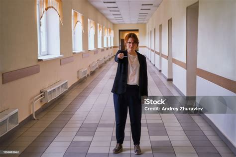선생님은 빈 학교 복도에 서 있습니다 여성 학교 교사는 당신을보면서 포인터를 보여줍니다 독감 바이러스 전염병으로 인한 고립의 개념 집회실에 대한 스톡 사진 및 기타 이미지