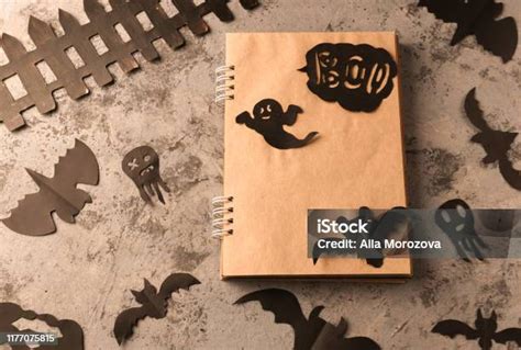 콘크리트 표면에 검은 종이로 조각 된 검은 박쥐와 유령의 그림 공예 시트와 복사 공간이있는 메모장 할로윈 축하 개념에 대한 공예품입니다 Handwork 플랫 레이 10월에