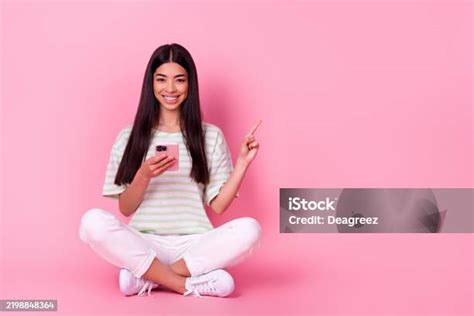 긍정적 인 좋은 사람의 전체 길이 초상화는 바닥 사용 전화 손가락 빈 공간을 표시하고 분홍색 배경에 고립 된 손가락 빈 공간을 나타냅니다 18 19세에 대한 스톡 사진 및