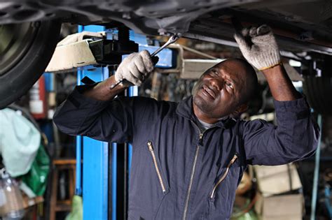 남자 기술자 자동차 정비사는 제복을 입고 정비를 점검하며 수리 차고 역에서 자동차 서비스를 들어 올렸습니다 손전등과 렌치 고정 고장 차량을 사용하는 작업자 자동차 수리