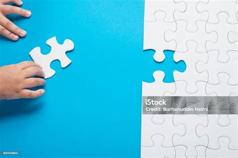 파란색 배경에 흰색 퍼즐의 조각을 들고 하는 아기 손 비즈니스와 팀 작업 개념입니다 조각그림 맞추기에 대한 스톡 사진 및 기타