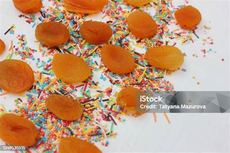 흰색 배경에 테두리와 말린 살구를 뿌려 장식합니다 구석에 여러 가지 색 설탕 과자 분말과 말린 살구 흩어져있는 달콤한 설탕 스틱과 공 0명에 대한 스톡 사진 및 기타 이미지