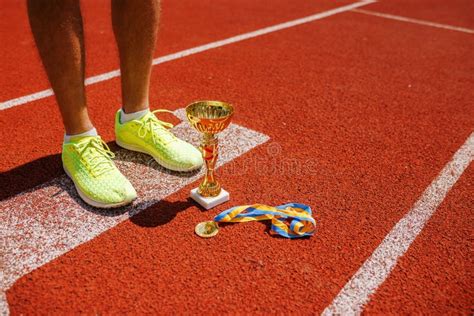 A Triumphant Athlete With A Trophy On The Athletics Field His Legs