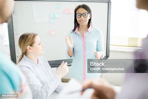 셔츠와 동료 앞에 서 있는 회의에서 아이디어를 공유 하 고 안경에 웃는 아름 다운 젊은 흑인 관리자 계획에 대한 스톡 사진 및 기타 이미지 Istock