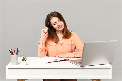 메모를 쓰고 앉아서 회색 배경에 고립 된 Pc 노트북으로 흰색 책상에서 일 하는 젊은 파스텔 캐주얼에서 여자 의아해 성취 비즈니스 커리어 라이프 스타일 컨셉 복사 공간을