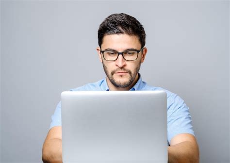 Retrato De Homem Concentrado Sério Trabalhando No Laptop E Sentado à Mesa Isolado Em Cinza