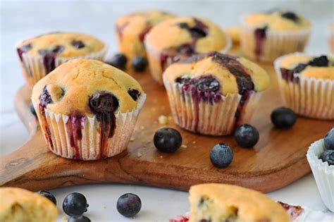 신선한 블루베리 대리석 효과 배경으로 둘러싸인 나무 도마에 종이 케이크 케이스에 배치 홈메이드 블루베리 머핀의 클로즈업 이미지