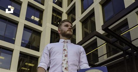 흰색 버튼 업 셔츠와 갈색 바지를 입은 남자가 낮 동안 보도에 서 있다 사진 Unsplash의 무료 불사조 이미지