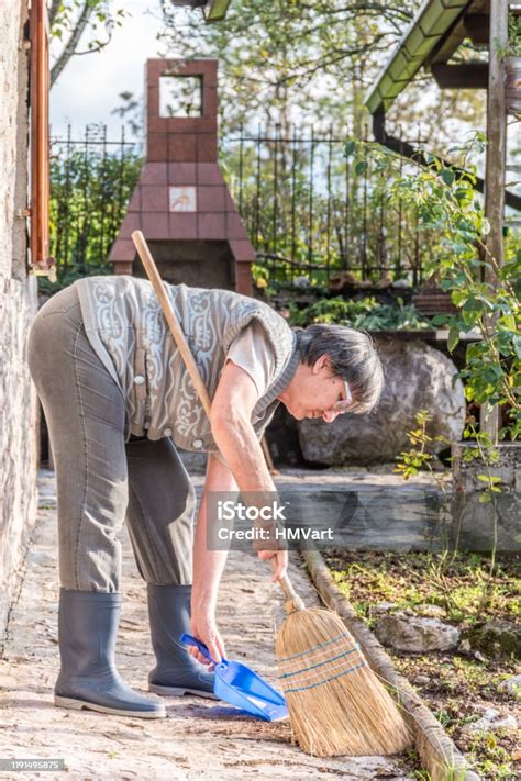 고리버들 빗자루와 함께 집 길에 흙과 나뭇잎을 청소하는 선임 여성 노인에 대한 스톡 사진 및 기타 이미지 노인 빗자루 야외 Istock