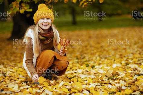 갈색 스웨터와 모자를 쓰고 가을 잎을 모으는 행복한 소녀 10월에 대한 스톡 사진 및 기타 이미지 10월 11월 8 9
