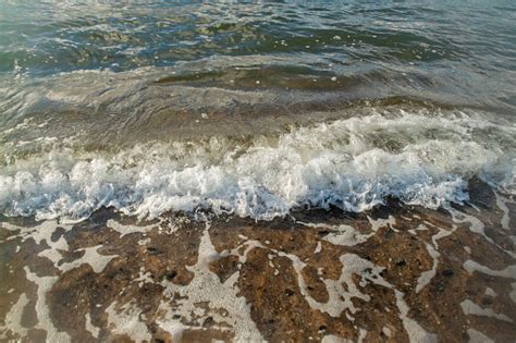 자갈 해변에 흐르는 하얀 거품이 있는 바다 파도의 클로즈업 해변에서의 해변 휴가와 가족 주말을 주제로 수정처럼 맑은 물과 바다 바위가 있는 배경 0명에 대한 스톡 사진 및