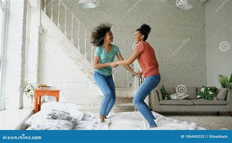 Mixed Race Young Beautiful Girls Dancing On A Bed Together Having Fun