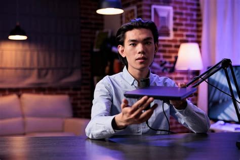 팟캐스트 스테이션에서 노트북 리뷰를 녹음하는 남성 블로거 인터넷 채널에서 컴퓨터 제품 추천 동영상을 촬영합니다 소셜 미디어용 콘텐츠 제작 라이브 스트리밍 방송