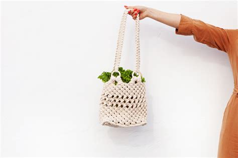 소녀는 비닐 봉지없이 야채 채소와 메쉬 쇼핑 백을 들고있다 제로 폐기물 플라스틱 무료 환경 친화적 인 개념 수제 마크라메 백 지속 가능한 라이프 스타일 가방에 대한 스톡