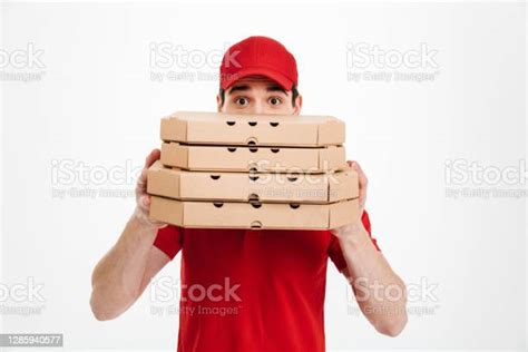 빨간 티셔츠와 모자를 쓰고 흰색 배경에 고립된 피자 상자 더미로 얼굴을 덮는 모자를 쓴 젊은 배달원이미지 T 셔츠에 대한 스톡 사진 및 기타 이미지 Istock