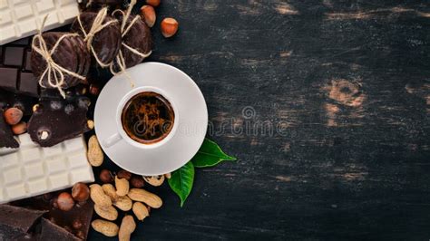 Чашка кофе и комплект шоколада с печеньями и помадками На черной деревянной предпосылке Стоковое