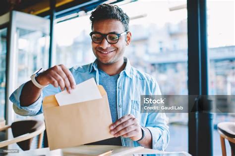봉투를 풀는 동안 커피 숍에서 여가 시간을 보내는 더 나은 시력을 위한 안경에 잘 생긴 성공적인 지능형 사업가 좋은 찾고 웃는 남성 사람 즐기는 로 소포 실내 봉투에 대한
