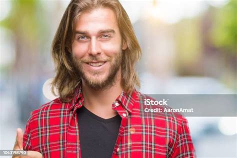 행복 한 엄지손가락 손으로 제스처를 하 고 격리 된 배경 위에 긴 머리를 가진 젊은 잘생긴 남자 승인 성공을 보여주는 카메라를 보고 하는 식 긍정적인 감정 표현에 대한 스톡