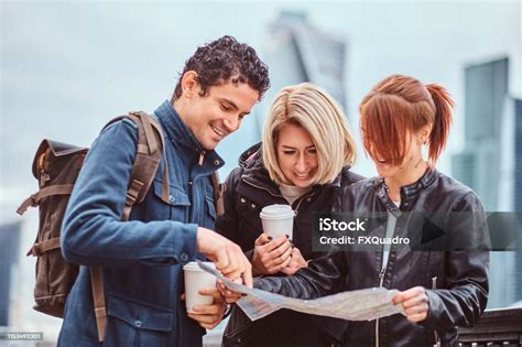 Group Of Happy Tourists Searching Place On The Map In Front Of