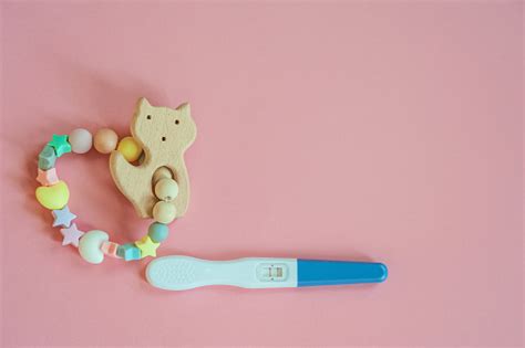 구슬과 임신 테스트와 나무 아기 이빨 나무 장난감 고양이 고립 된 분홍색 배경과 미니멀 플랫 누워 어린이와 부모를 즐겁게장난감