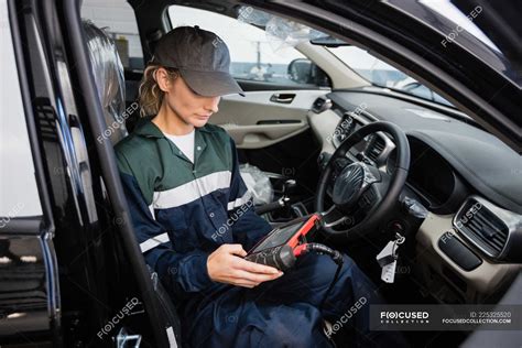 Female Mechanic Using Electronic Diagnostic Device In Repair Garage Examining Automotive