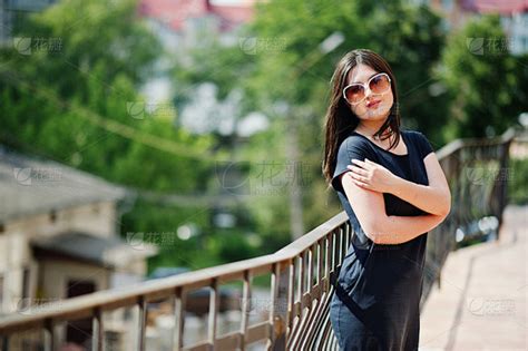 深色头发的女孩在城市的街道上摆姿势。