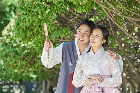 Foto De 한국의 전통적인 한복을 입고 나무 그늘 밑에서 서있는 모습 젊고 아름답고 우아한 모습의 아시아 한국 남녀 모델 Do Stock Adobe Stock