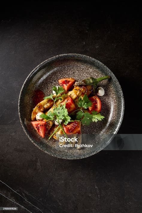 토마토 고수 치즈로 보완된 완벽하게 구운 가지의 수직 평면도가 현대적인 검은색 대리석 배경의 돌 접시에 전시되어 있습니다 가지 채소에 대한 스톡 사진 및 기타 이미지