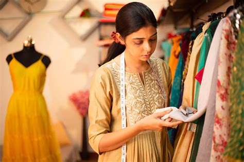 젊은 행복한 인도 여성 재단사 재봉사 패션 디자이너 드레스 확인 옷 스티치 의류 작업장 아틀리에 또는 스튜디오에서 목에 측정