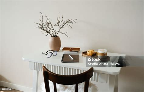 매력적인 도자기 꽃병 마른 나뭇가지 종이 부활절 달걀 세라믹 토끼 공책 유리잔 커피잔 나무 스탠드에 놓인 크루아상이 있는 아늑하고 미니멀한 작업 공간입니다 가구에 대한 스톡