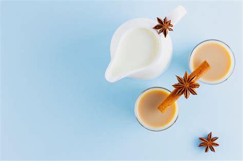 파란색 배경에 우유와 향신료를 곁들인 차 터키 티컵에 마살라 차이 파스텔 배경에 인도 국가 음료와 우유 주전자 공간을 복사합니다