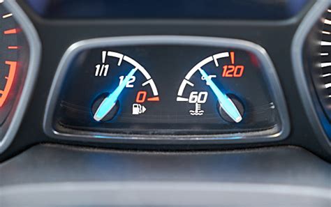 차량의 현재 연료량과 엔진 온도를 나타내는 생생한 파란색과 빨간색 강조 표시와 함께 연료 및 온도 게이지를 표시하는 자동차 대시보드의 클로즈업입니다 0명에 대한 스톡 사진