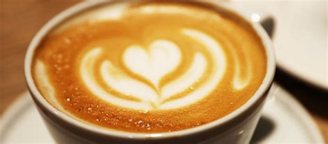 커피숍의 나무 테이블에 흰색 세라믹 컵에 아름 다운 꽃 하트 패턴이 있는 크림 같은 카푸치노의 근접 촬영 공간을 복사합니다 보케를 사용한 선택적 초점 0명에 대한 스톡 사진