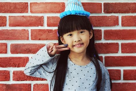 Premium Photo Portrait Of Innocent Girl Standing Against Brick Wall