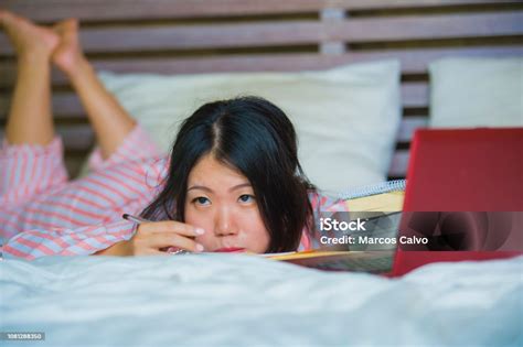 젊은 좌절과 피곤 아시아 일본 대학 학생 여자 지 루 느낌 및 생각 하 고 침대에 누워 집 침실에 잠겨있는 노트북 컴퓨터와 함께