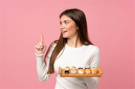 Молодая девушка с суши на розовом фоне намереваясь реализовать решение поднимая палец вверх