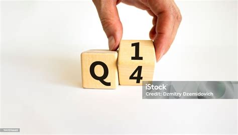 4 분기부터 1 분기까지의 상징 사업가는 나무 큐브를 돌리고 Q4라는 단어를 Q1로 바꿉니다 아름 다운 흰색 테이블 흰색 배경입니다 비즈니스 행복한 1분기 Q1 개념 복사