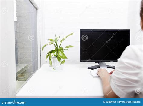 Вид сзади молодой коммерсантки используя компьютер на столе Стоковое Фото изображение