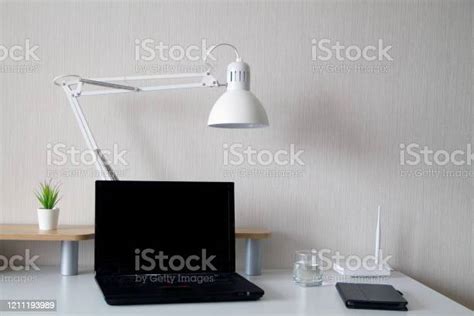 현대 작업 사무실의 내부 흰색 테이블에 작은 식물 물 한 잔과 검은 노트북 흰색 램프 데스크톱 조직 0명에 대한 스톡 사진 및