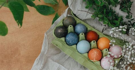 꽃이 있는 소박한 테이블에 있는 카톤 트레이에 천연 염료 부활절 달걀 현대 노란색 분홍색 파란색 및 회색 부활절 달걀은