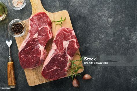 생 쇠고기 스테이크 어두운 콘크리트 배경의 도마에 로즈마리 소금 후추를 곁들인 차돌박이 생 신선한 립아이 스테이크 생 쇠고기 스테이크와 요리 용 향신료 0명에 대한 스톡