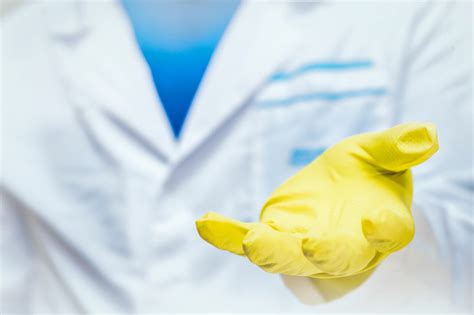 의료 가운을 입은 한 남자가 보호 장갑을 끼고 손바닥을 벌려 손을 내밀었다 빈 손 얼굴이 보이지 않습니다 의사는 도움과 치료를 제공합니다 가린 얼굴에 대한 스톡 사진 및