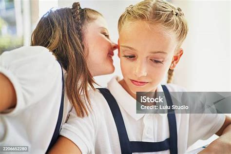 Schoolgirl Whispering A Secret To Her Classmate During Class Stock
