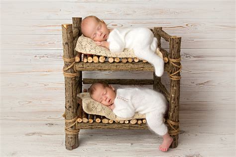 밝은 나무 배경에 흰색 보디 슈트를 입은 작은 신생아 쌍둥이 소년 신생아 쌍둥이는 이층 나무 침대에서 자고 있습니다 소년들 전문 스튜디오 사진 1개월에 대한 스톡 사진 및