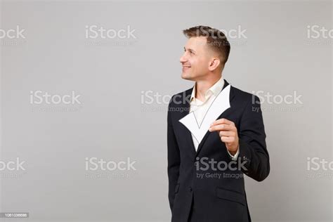 클래식 블랙에서 젊은 사업가 양복 셔츠 스튜디오에 회색 벽 배경에 고립 된 지주 확인 표시가 옆으로 찾고 성과 경력 부 비즈니스 개념입니다 복사 공간을 비웃는 다 검은색에