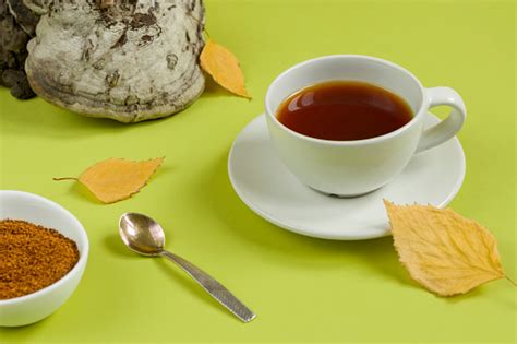 노란 배경에 흰색 컵에 치유 차 커피와 자작 나무 차의 조각 Naturopathy 대체 의학 면역을위한 트렌디 한 슈퍼 푸드