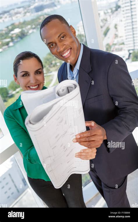 Confident Male And Female Architects Holding Blueprint Stock Photo Alamy