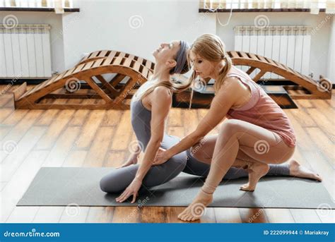женщина делает упражнения для растяжки йоги с помощью личного тренера по йоге в студии йоги