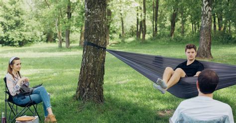 사회적 거리 두기 여름 공원에서 사회적 거리를두고 피크닉에서 대화를 즐기는 소수의 사람들 해먹과 나무 사이의 의자에서 차가워지는 친구들 신세계에서의 안전 모임 사진