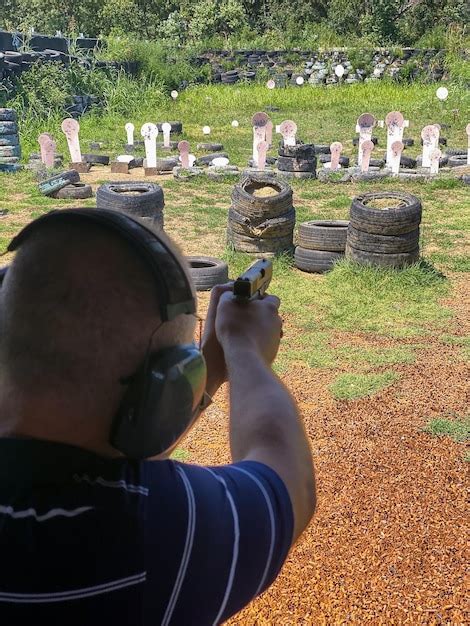 Premium Photo Man Firing Pistol At Target In Outdoor Shooting Range